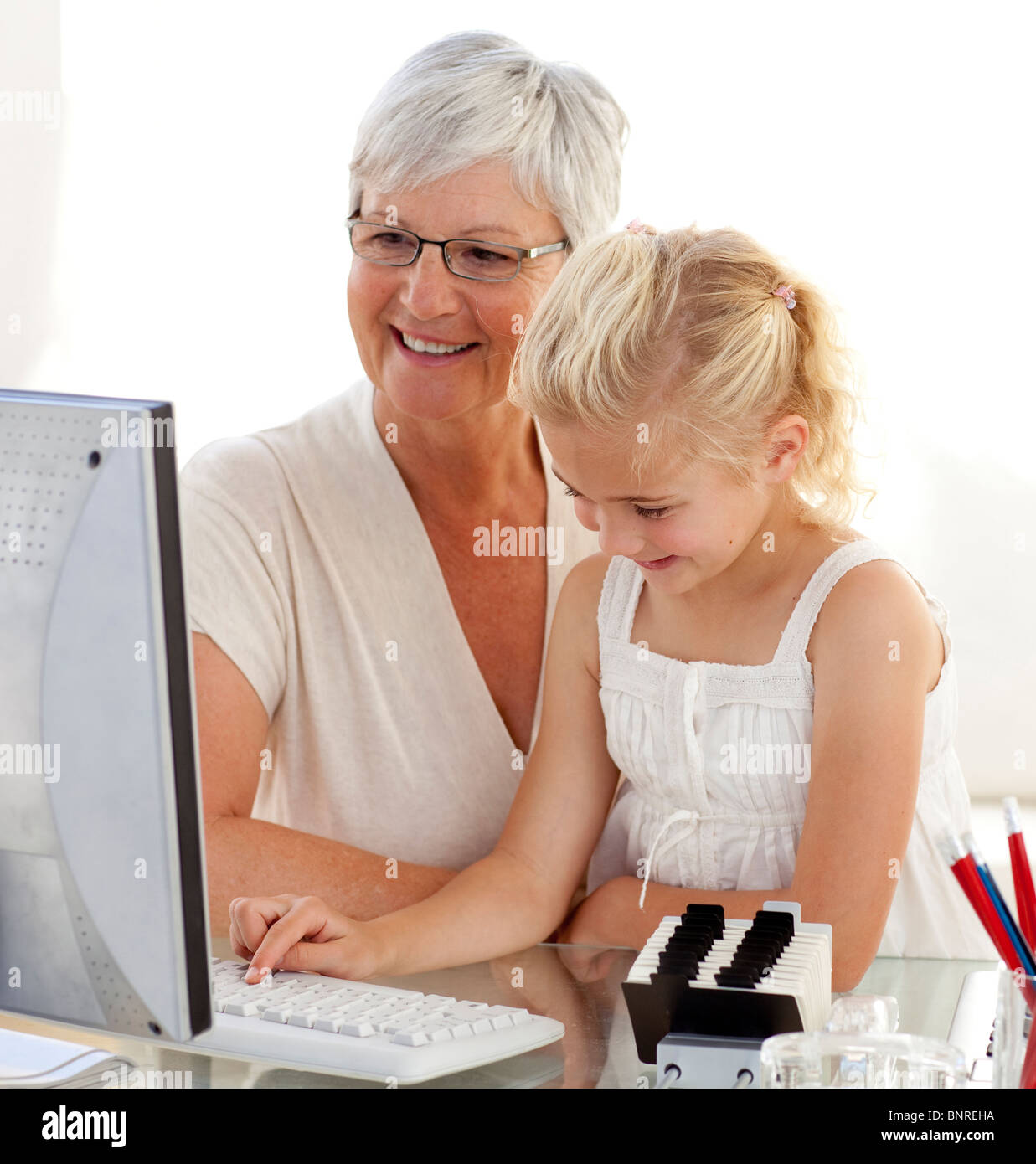 Granddaughter using a computer with her grandmother Stock Photo - Alamy