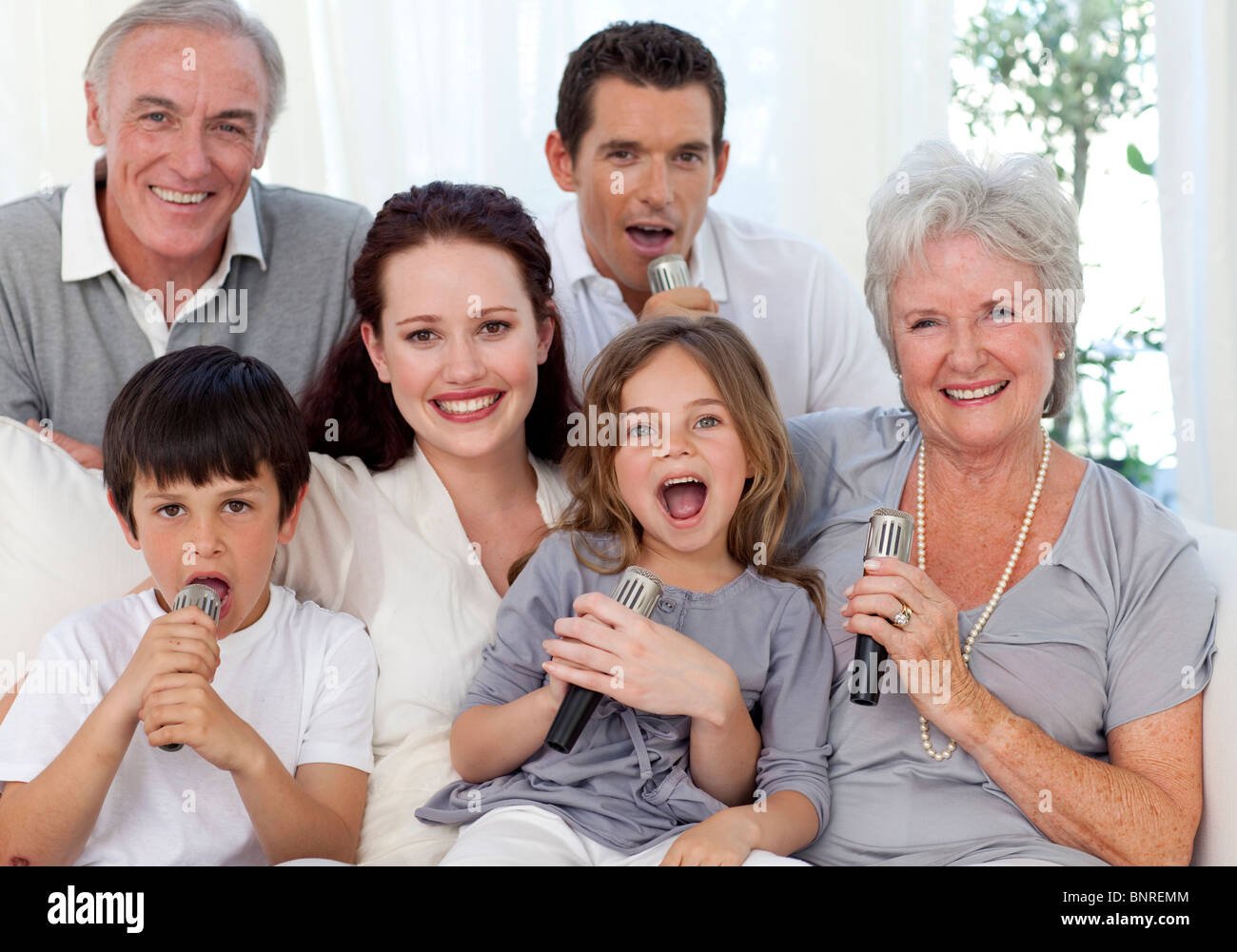 Happy family singing karaoke in living-room Stock Photo - Alamy
