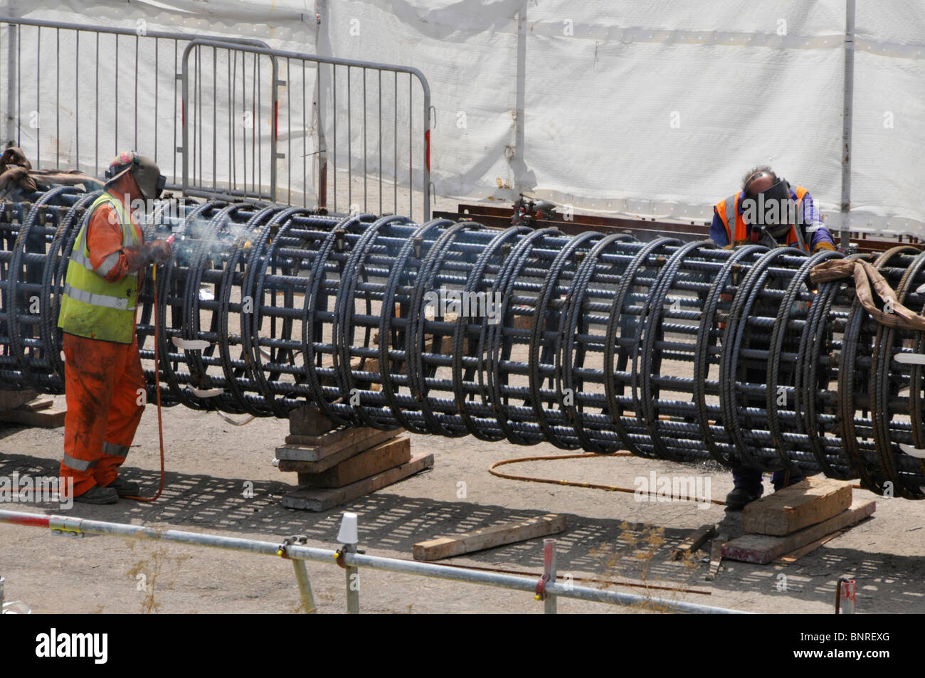 Men welding steel reinforcing rods for lowering into foundation piles ...