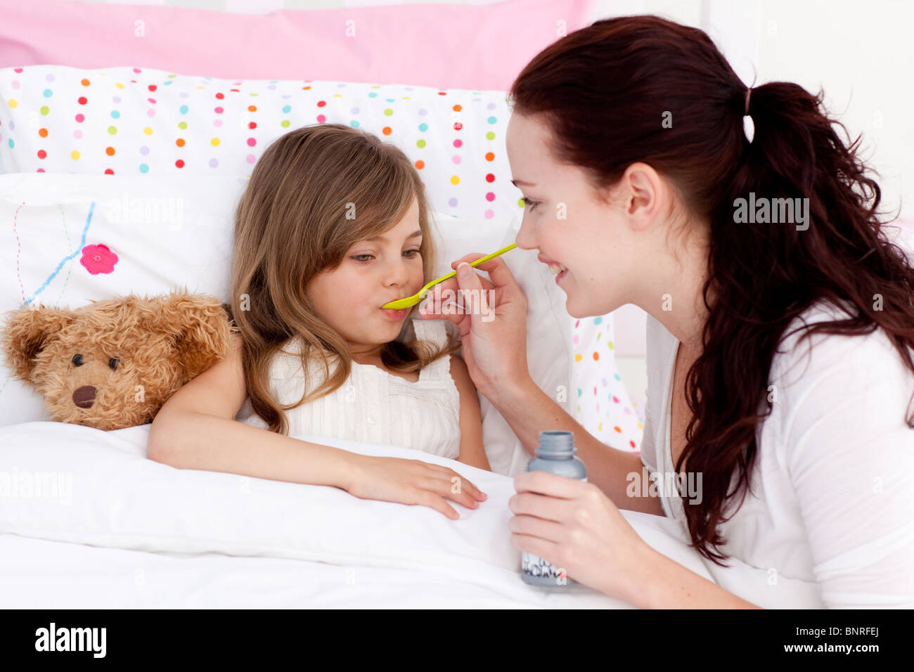 Little girl in bed taking syrup Stock Photo - Alamy