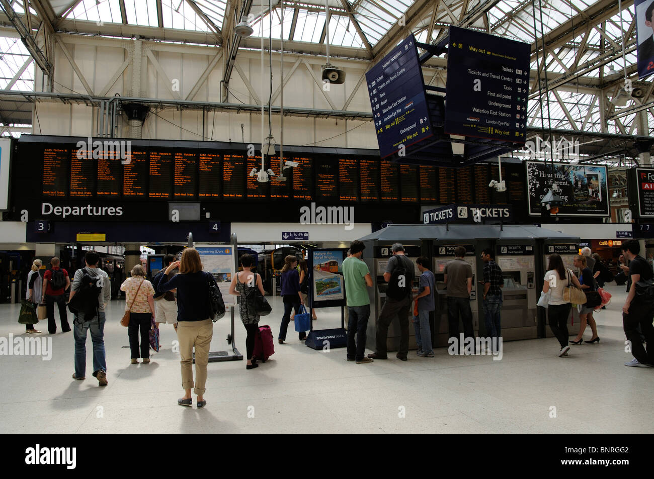 Customers using ticket machines and the train departures board on the ...