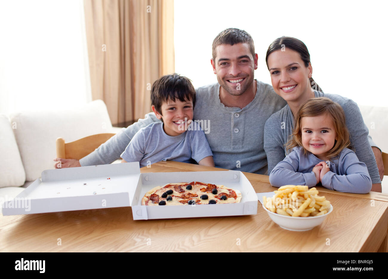Family eating pizza and fries at home Stock Photo - Alamy