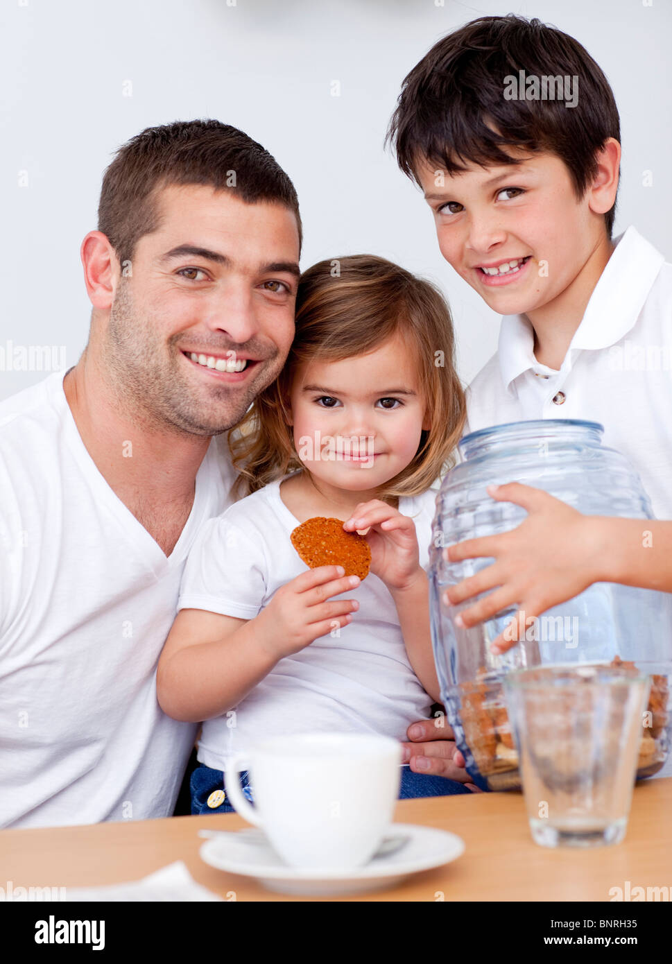 Father and children eating biscuits with milk Stock Photo - Alamy
