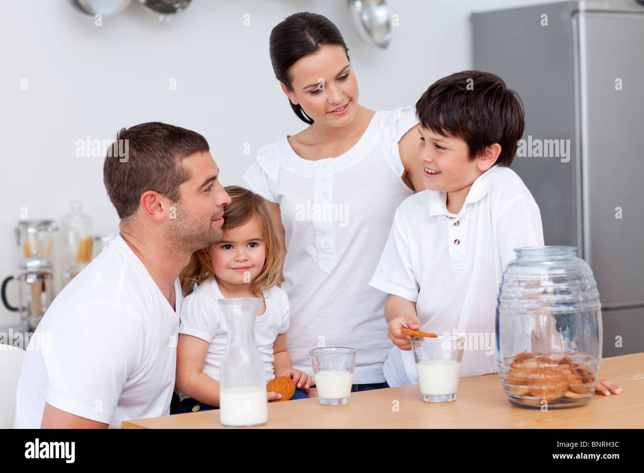 Parents and children eating biscuits and drinking milk Stock Photo - Alamy