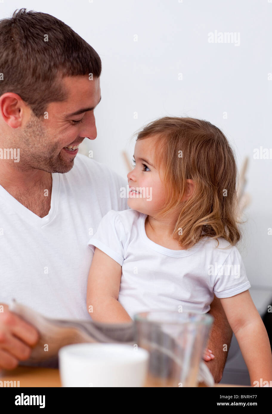 Father reading a newspaper smiling to his daughter Stock Photo - Alamy