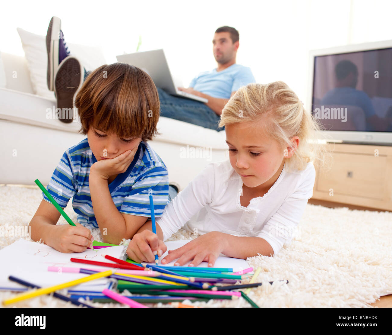 Children painting in living-room and father using a laptop Stock Photo ...