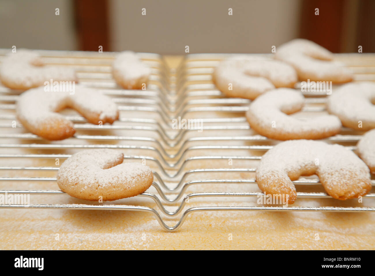 crescent cookies cooling on a baking rack sprinkled with powered sugar ...