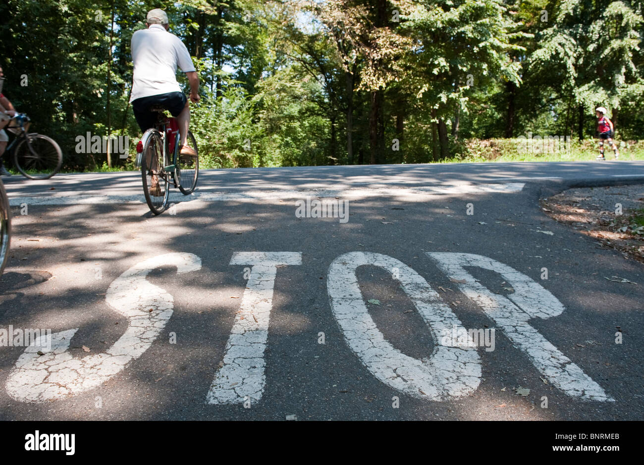 Stop sign on road and cyclist Stock Photo - Alamy