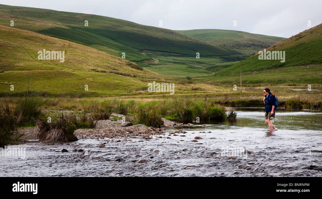 Female hiker crossing the Elan River on the Monks Trod ancient footpath ...