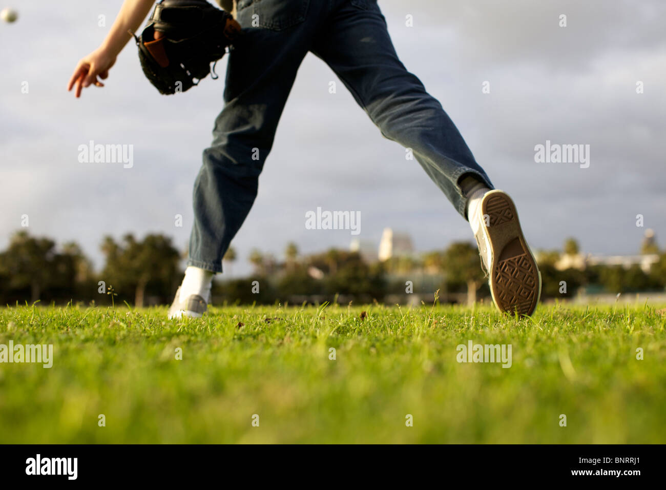 Kid's feet move as he throws the baseball back to his dad at the park ...