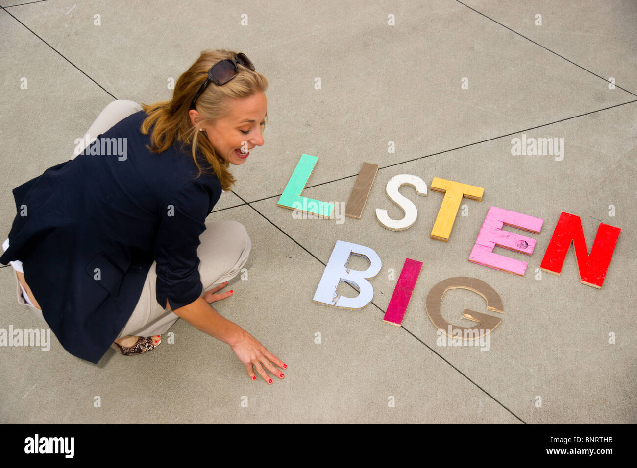Attractive Blonde woman spells out LISTEN BIG with ABC blocks Stock ...