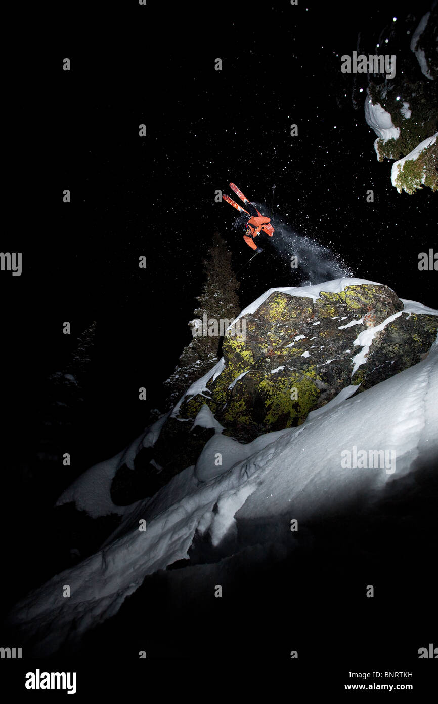 A male telemark skier front flips off a cliff at night in Montana Stock ...