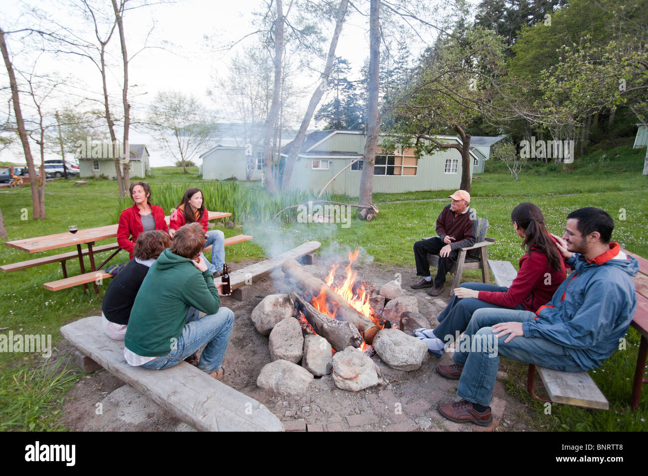 A group of 7 friends sit around a camp fire at a rustic resort Stock ...