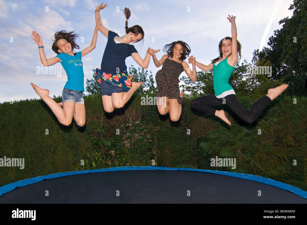 Horizontal close up portrait of a group of girl friends jumping on a ...