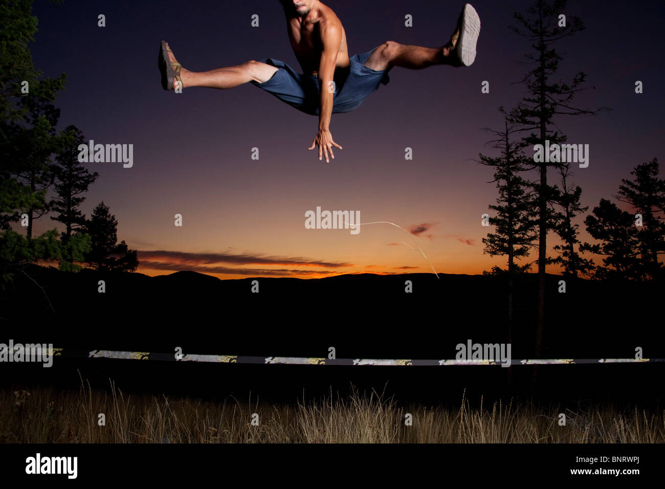 A professional slackliner plays around on the slackline in a field at ...