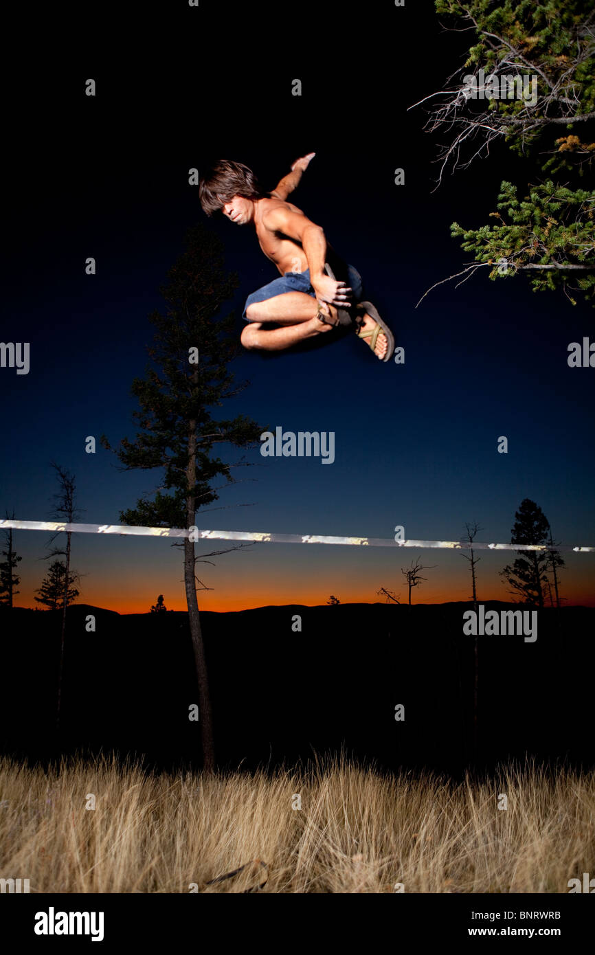 A professional slackliner plays around on the slackline in a field at ...