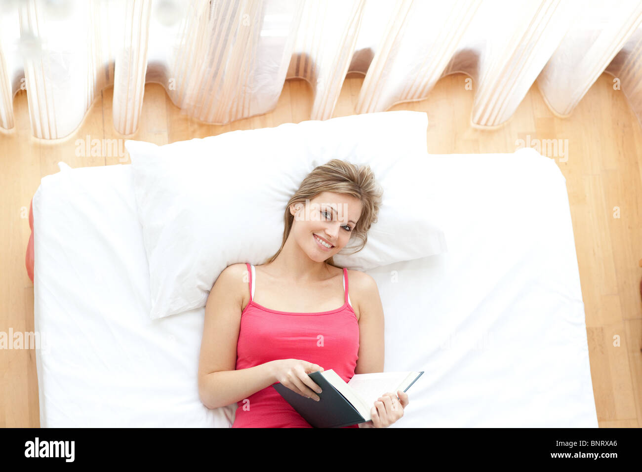 Radiant young woman reading a book Stock Photo - Alamy