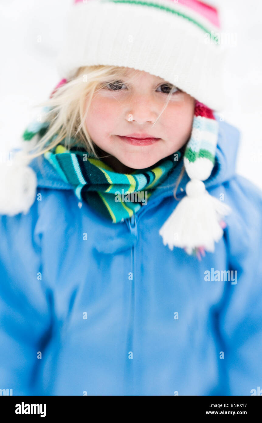 Young girl smilies with pink cheeks in the winter snow with select ...