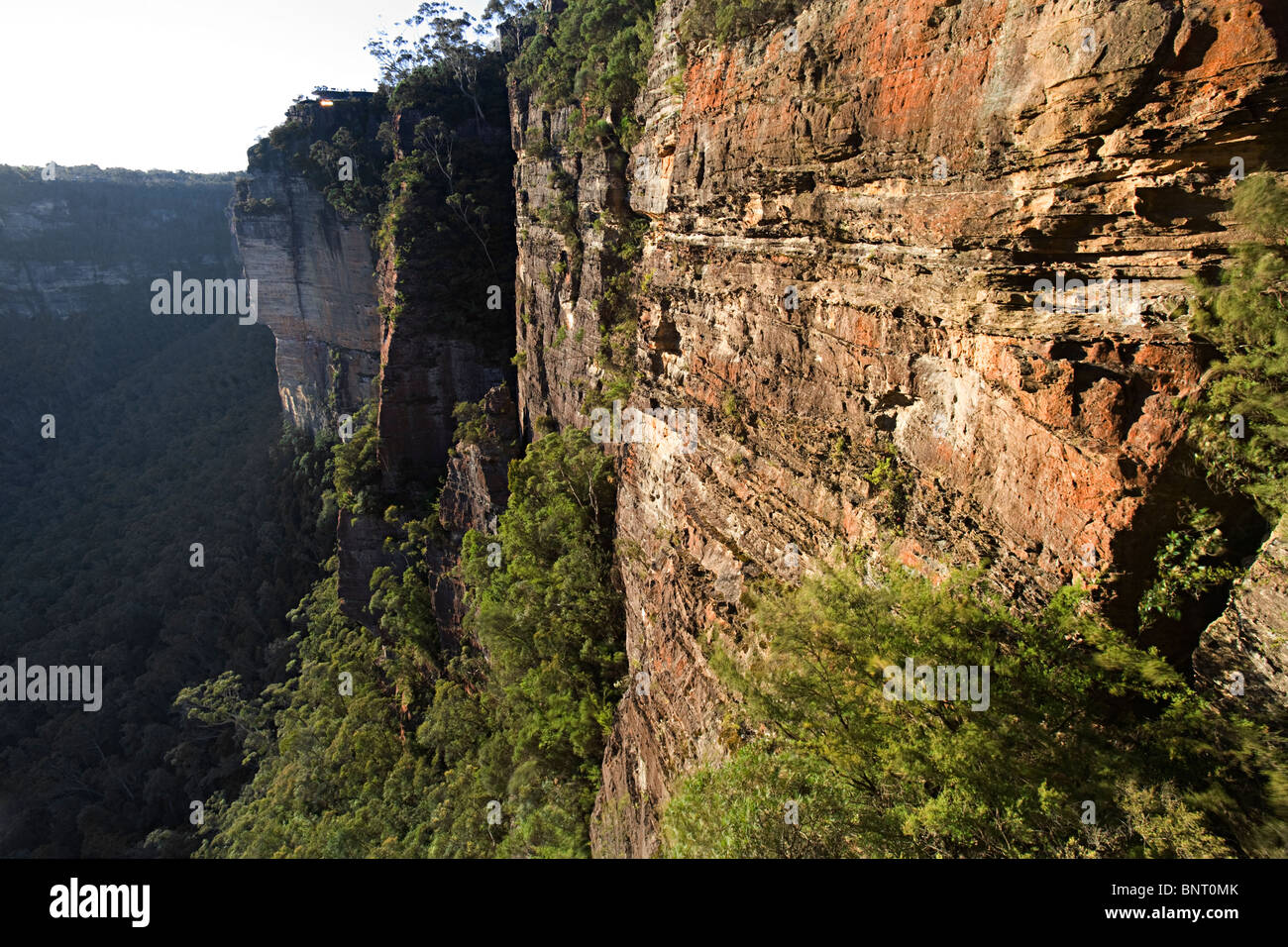 Large orange and grey cliff above jungle Stock Photo - Alamy