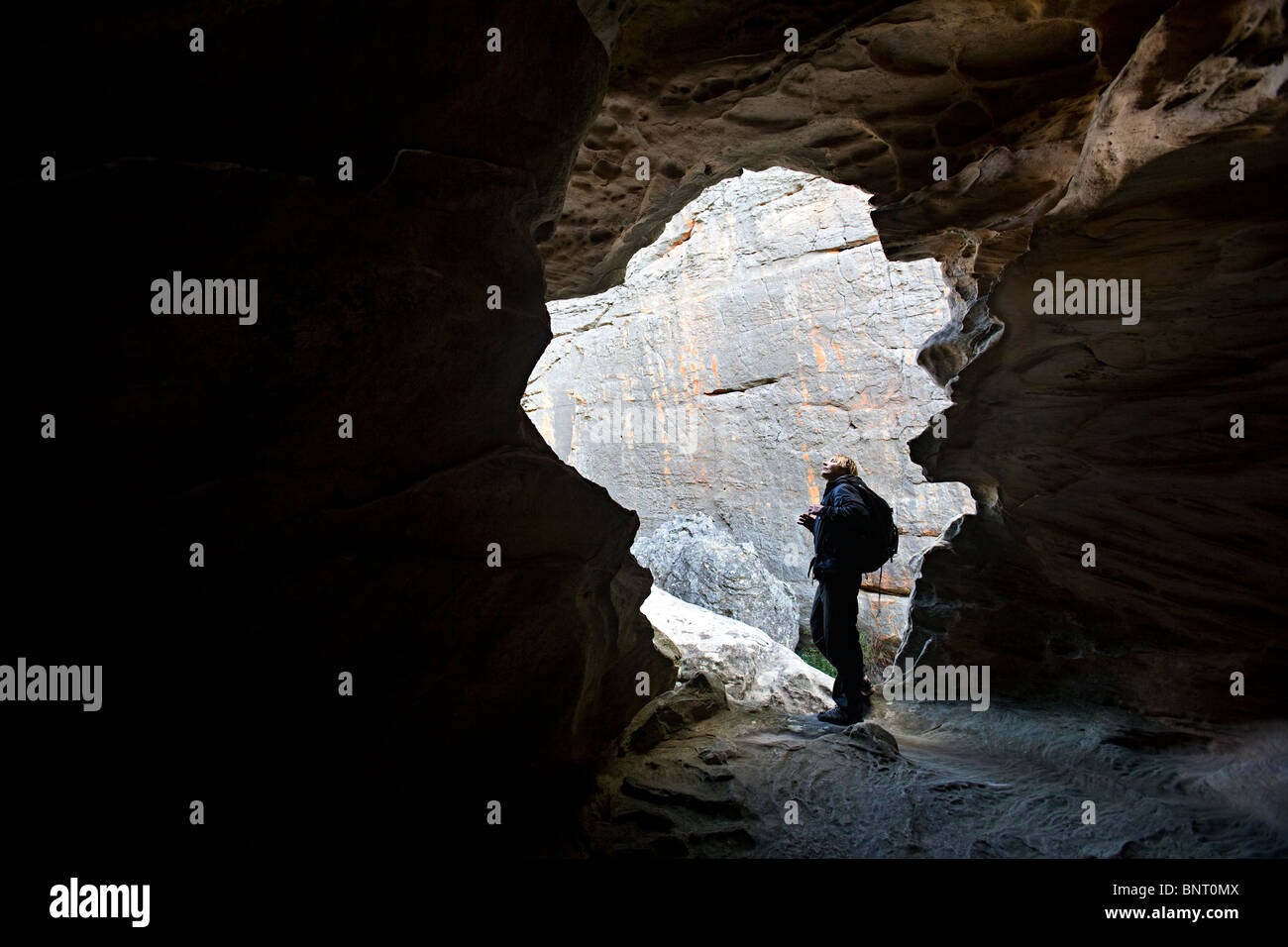 Man standing in the light of the entrance to cave Stock Photo - Alamy