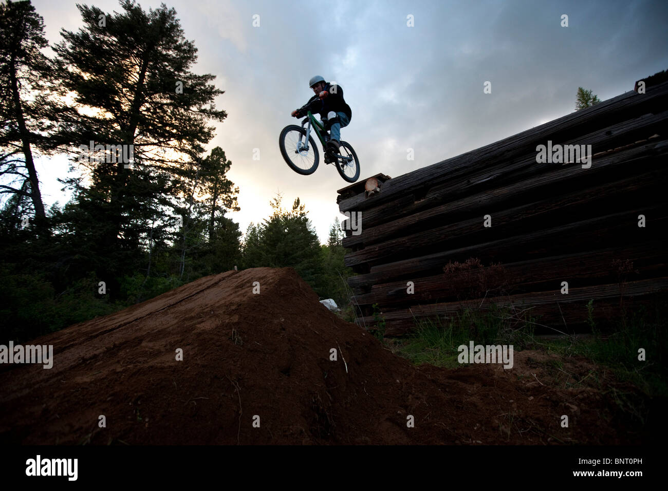 A mountain biker jumps off a log cabin in Idaho Stock Photo - Alamy