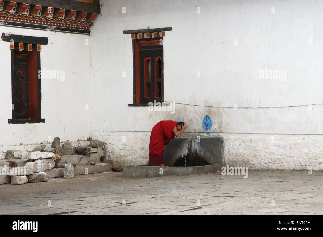 A monk washing himself in the corner of a courtyard in the Tashichho ...