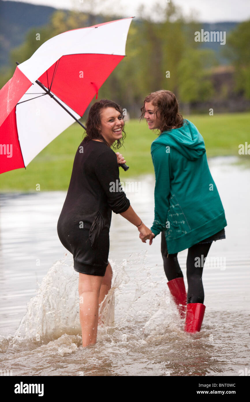 Two young women hold hands as they walk through a large puddle Stock ...