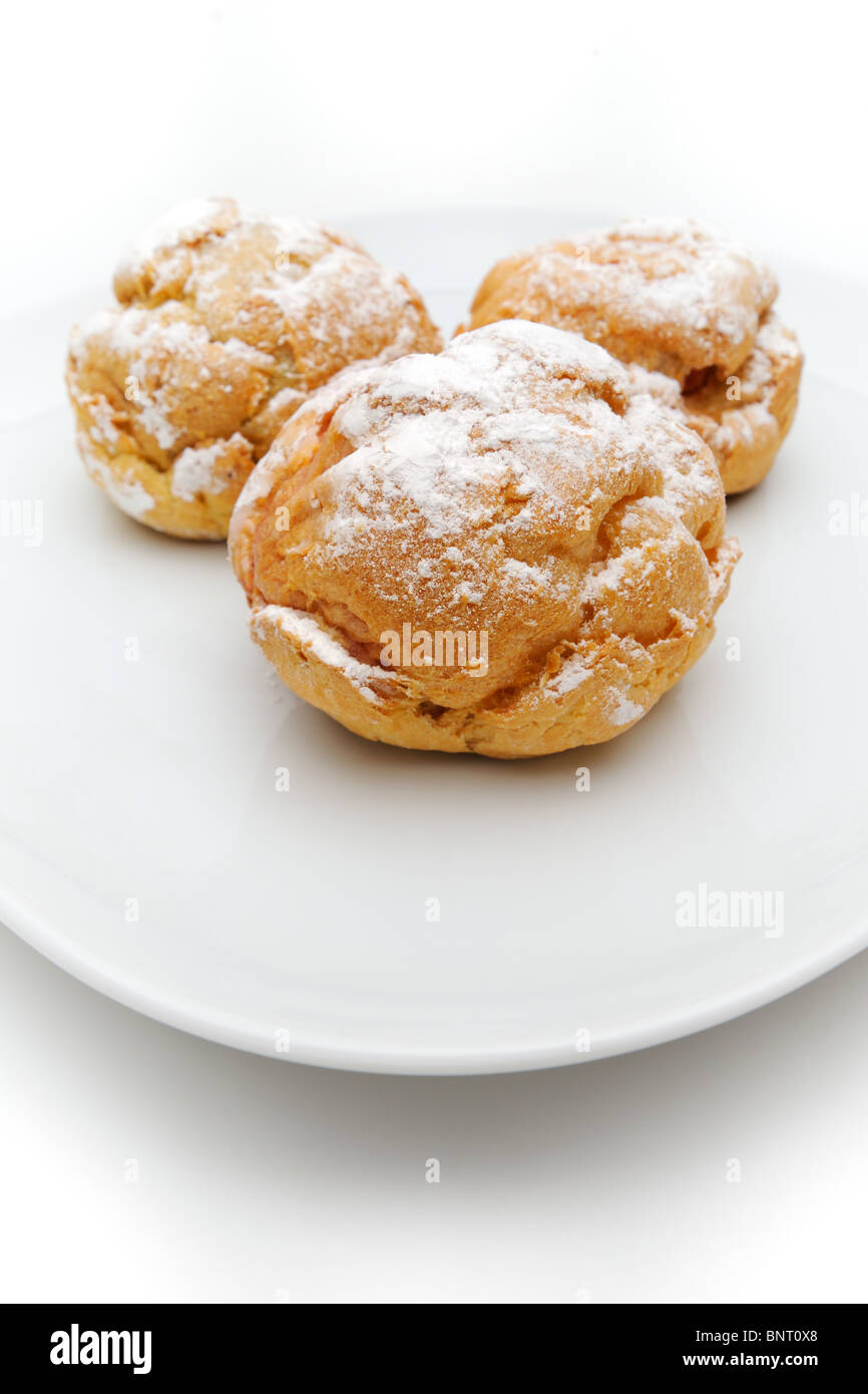Three profiteroles on a plate, isolated, white background Stock Photo ...