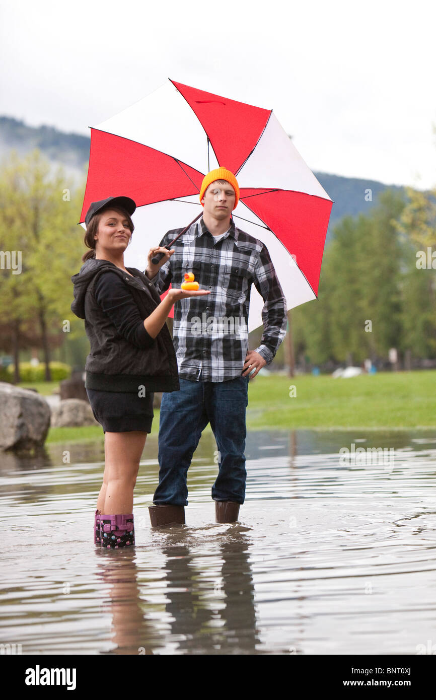 A portrait of two young adults standing in a puddle after having a fun ...