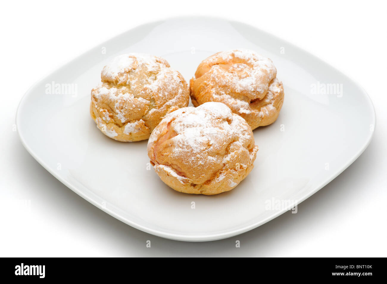 Three profiteroles on a plate, isolated, white background Stock Photo ...