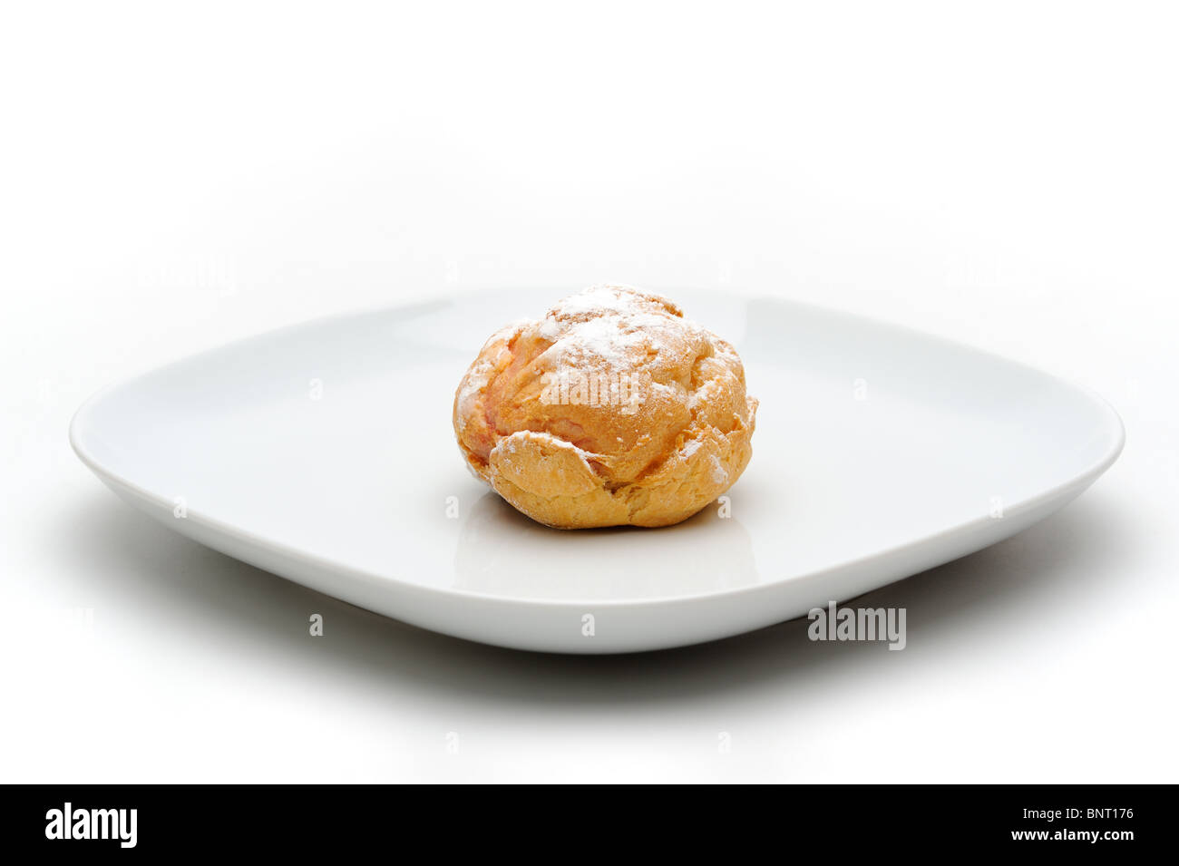Single profiterole on a plate, isolated, white background Stock Photo ...