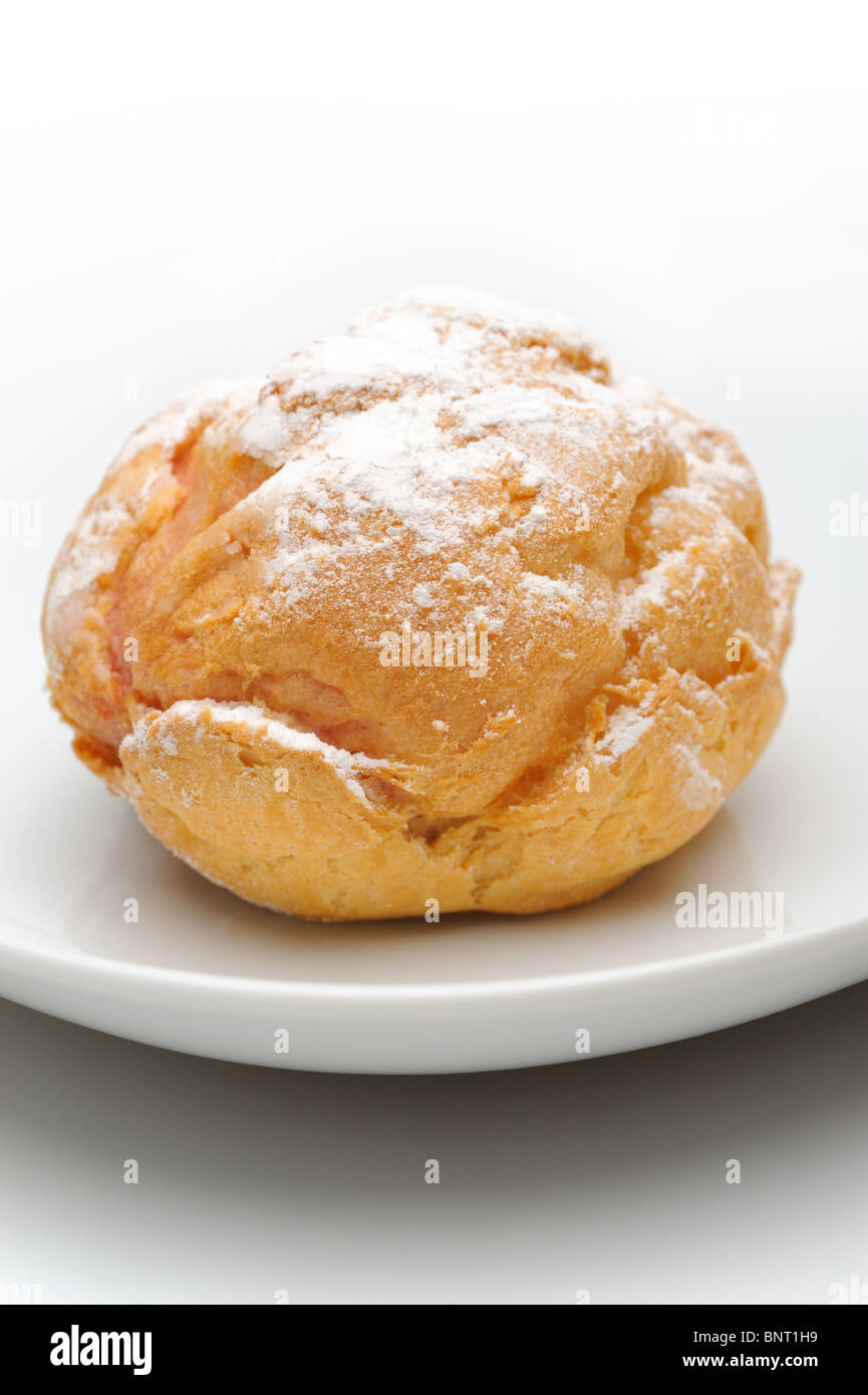 Single profiterole on a plate, isolated, white background Stock Photo ...