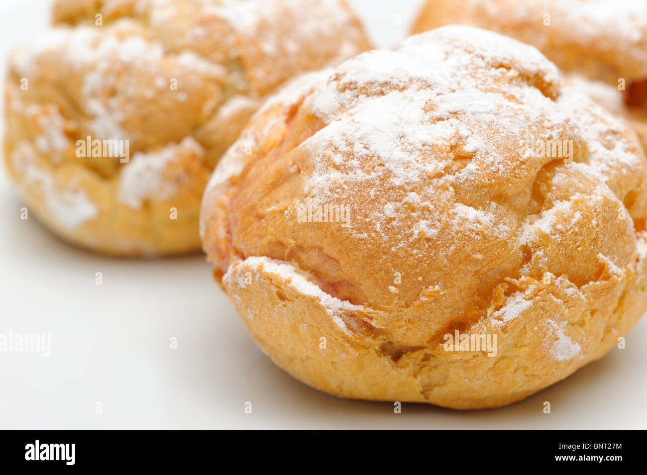 Three profiteroles on a plate, isolated, white background Stock Photo - Alamy