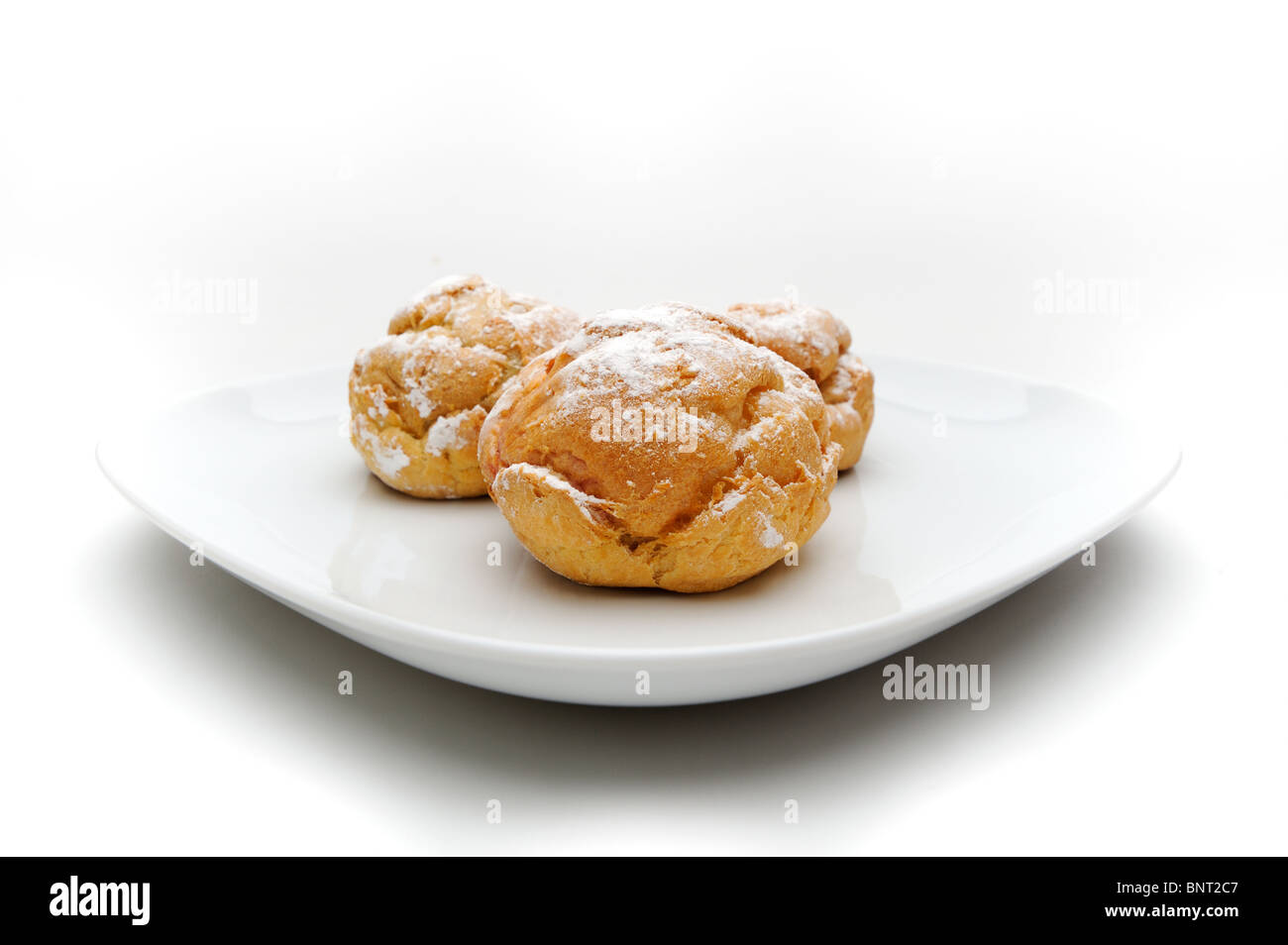 Three profiteroles on a plate, isolated, white background Stock Photo ...