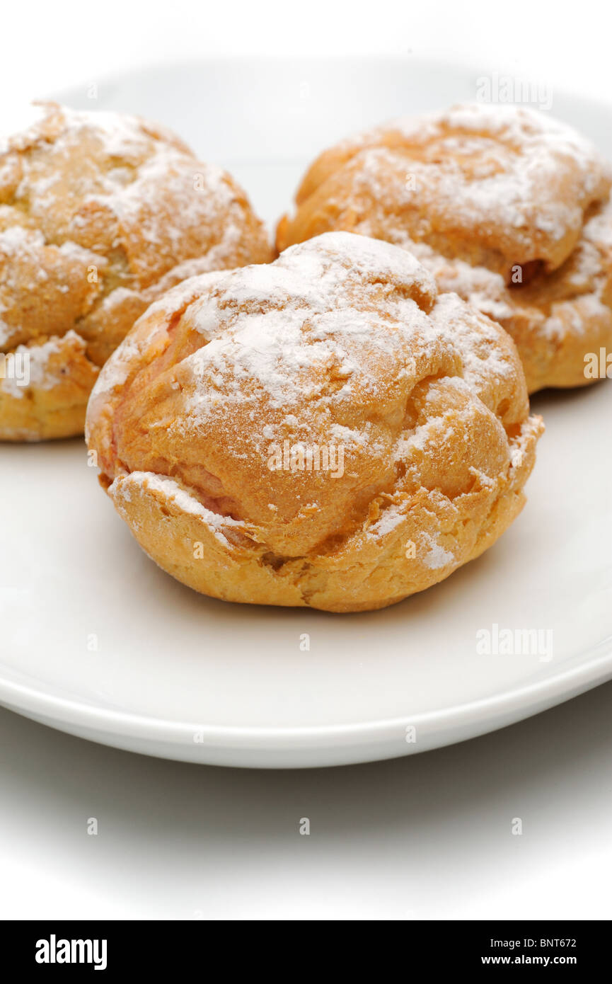 Three profiteroles on a plate, isolated, white background Stock Photo ...
