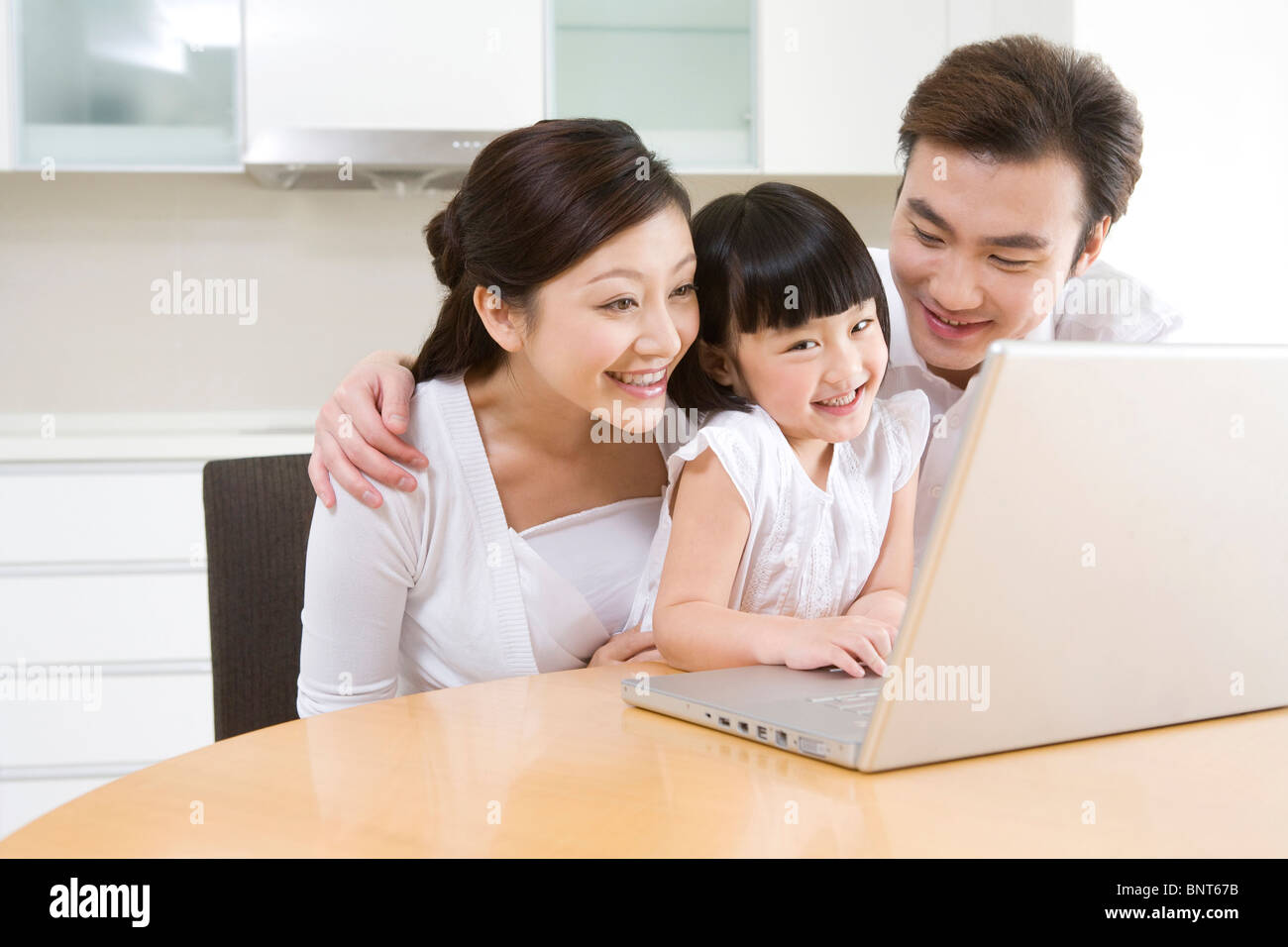 Little girl using laptop with her parents Stock Photo - Alamy