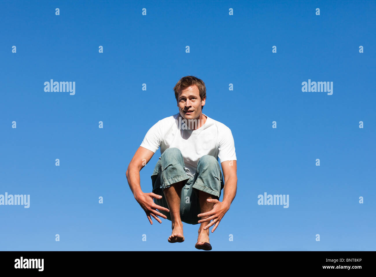 Handsome man jumping against a blue background Stock Photo - Alamy