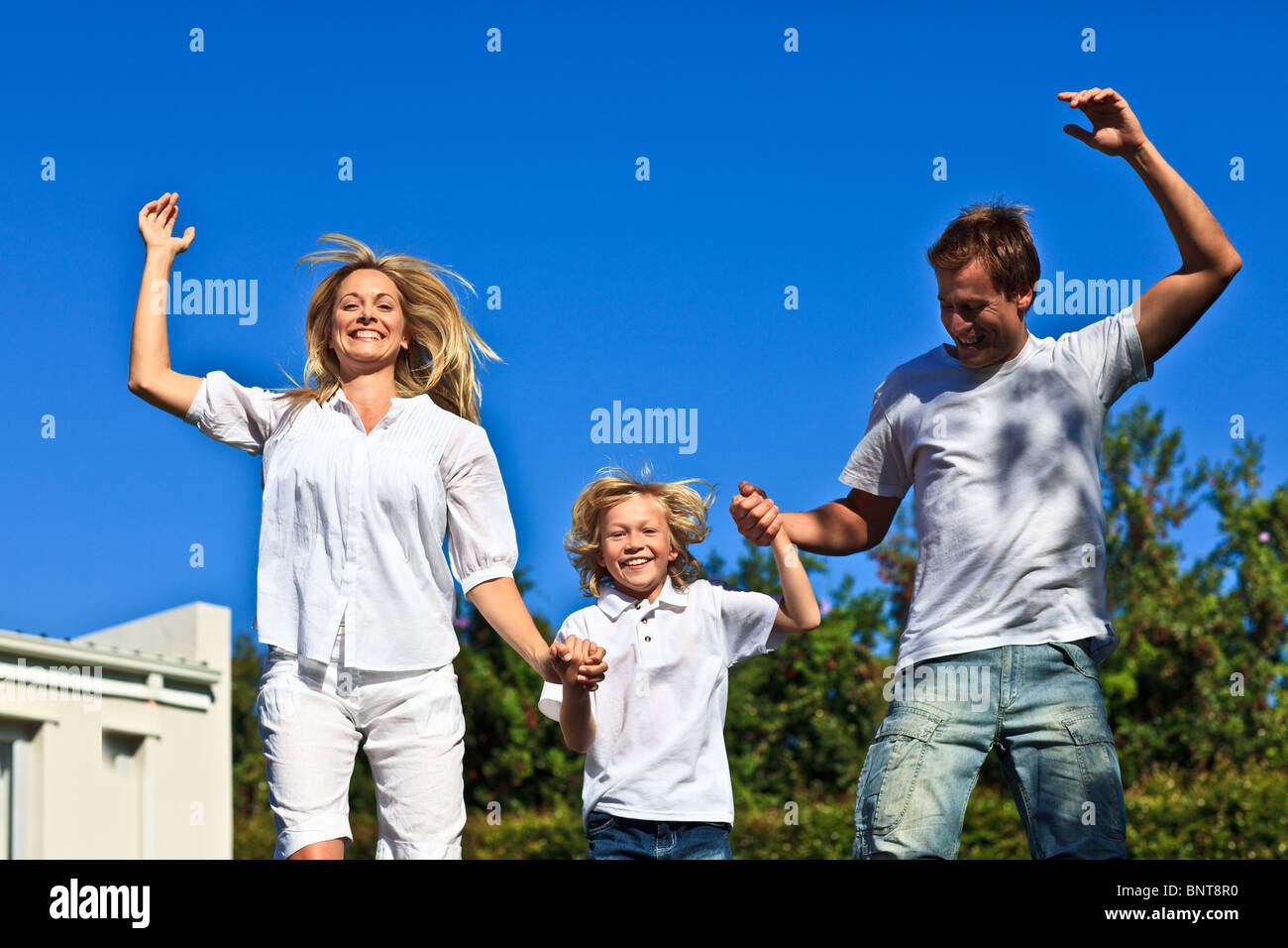 Happy family jumping against a blue background Stock Photo - Alamy