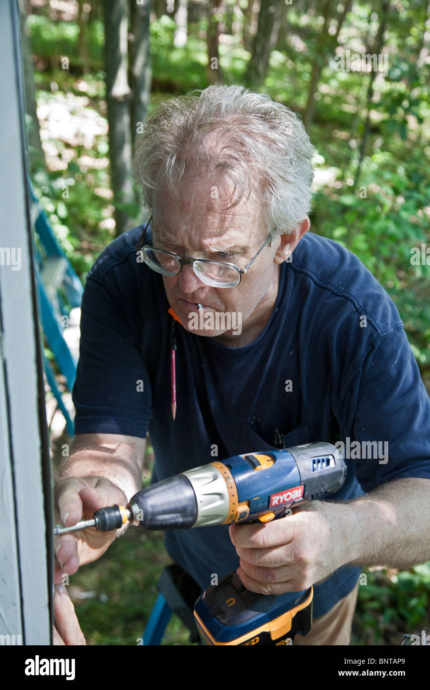 Prairieville, Michigan - A man uses a cordless drill to install a ...