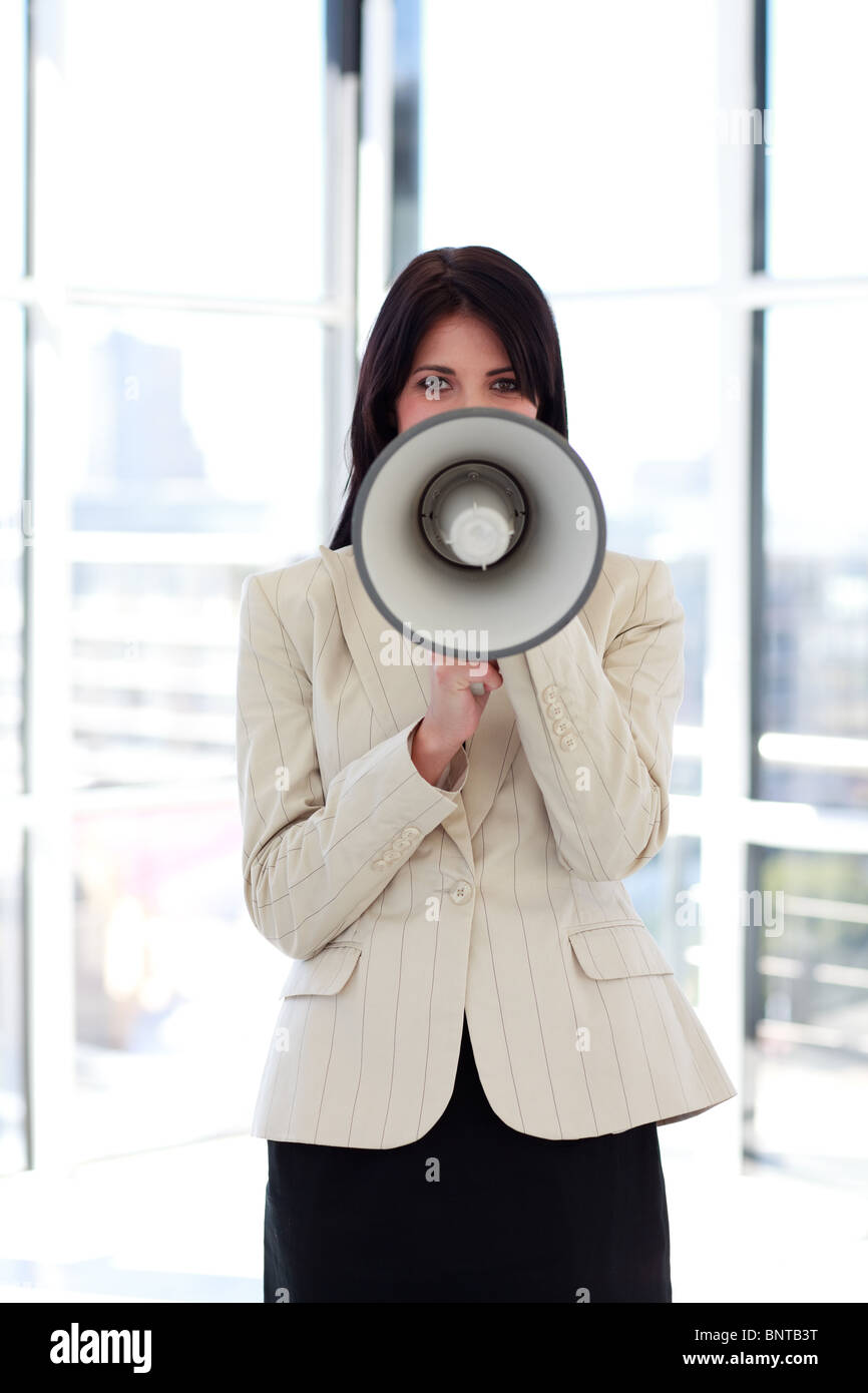 Beautiful businesswoman shouting through megaphone against misty green ...