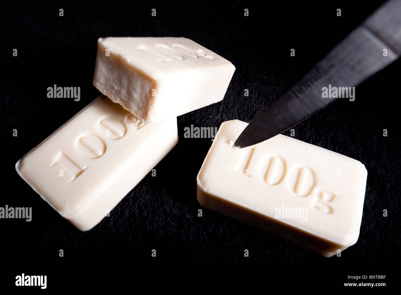 Three bars of plain soap stamped with 100g on a black towel Stock Photo ...