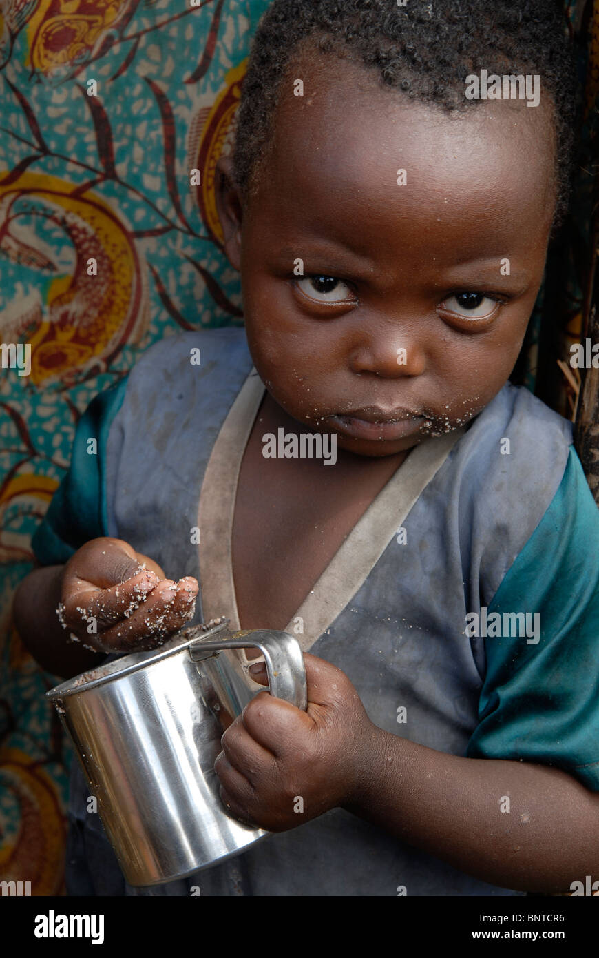 A displaced Congolese child eats mashed cassava with his hand in an IDP ...