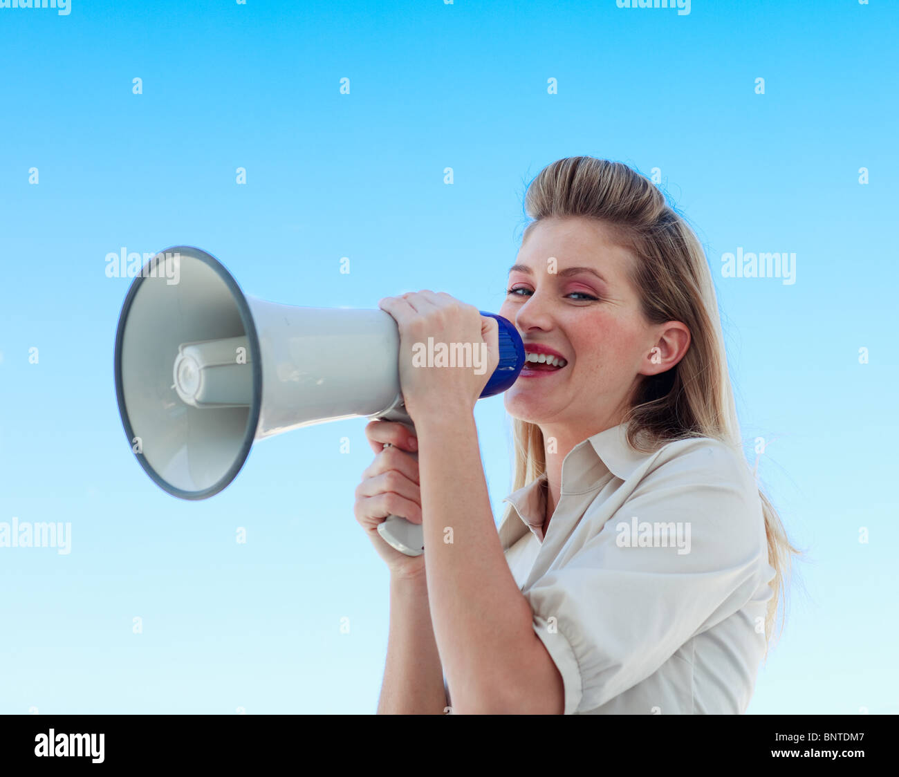 Beautiful businesswoman shouting through megaphone against misty green ...
