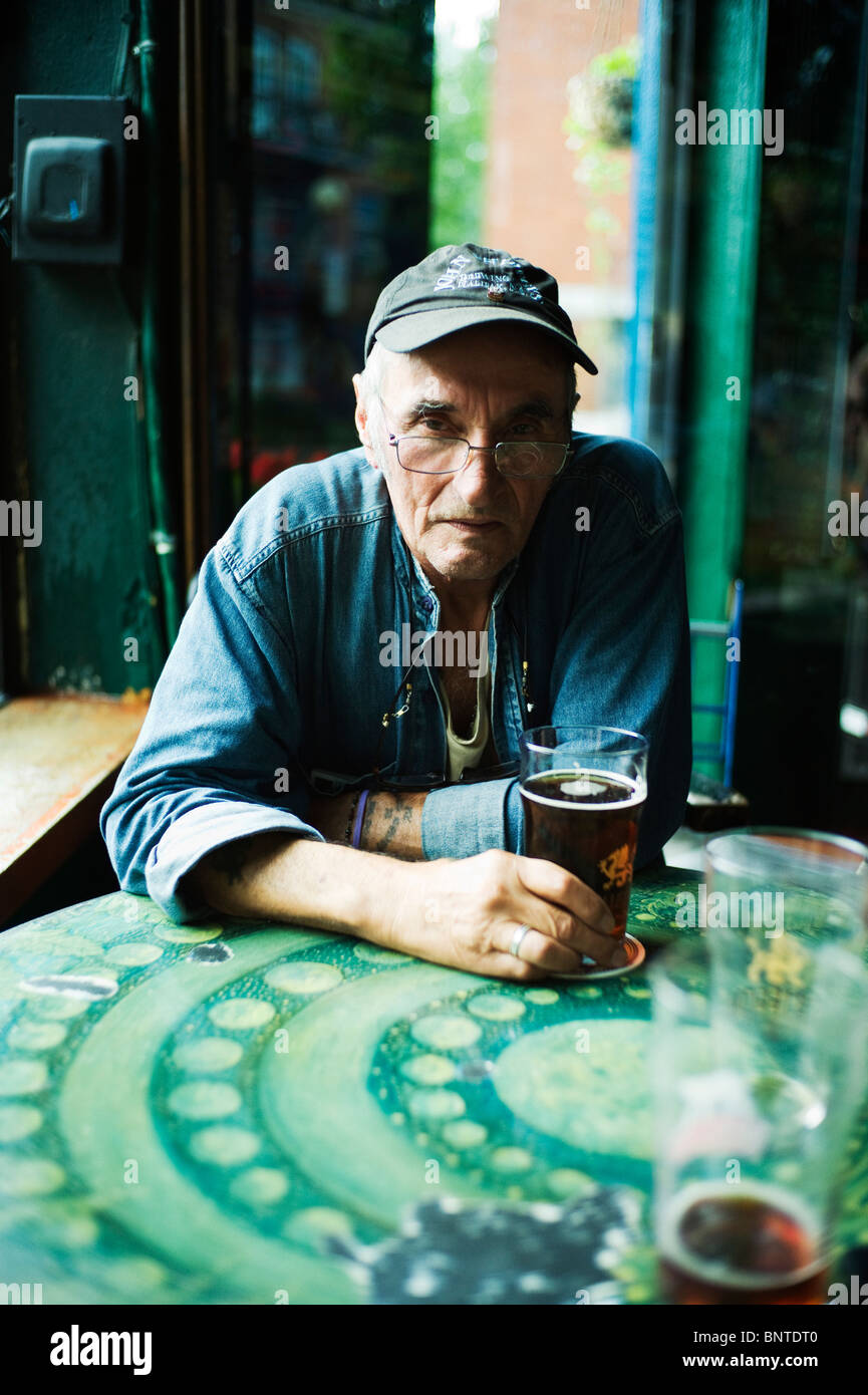 Old man at table in bar with hand on pint of beer Stock Photo - Alamy