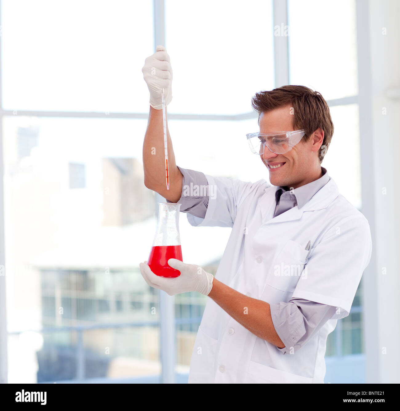 Smiling scientist examinig a test-tube Stock Photo - Alamy
