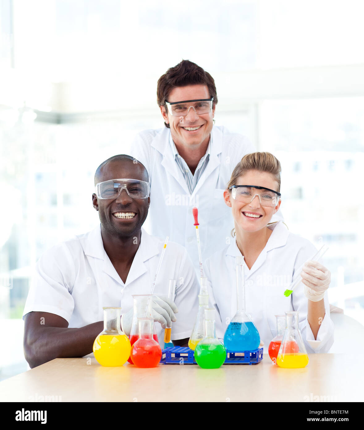 Smiling scientists examining test-tubes Stock Photo - Alamy