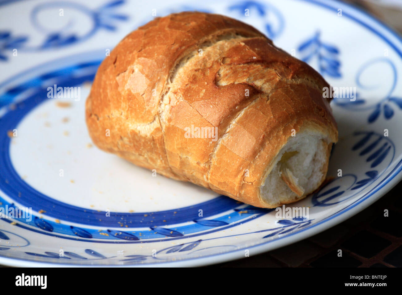 Bread roll on white and blue plate Stock Photo - Alamy