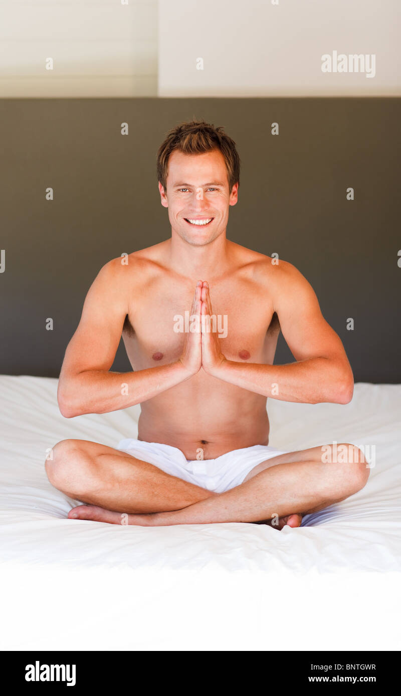 Smiling man meditating on bed Stock Photo - Alamy