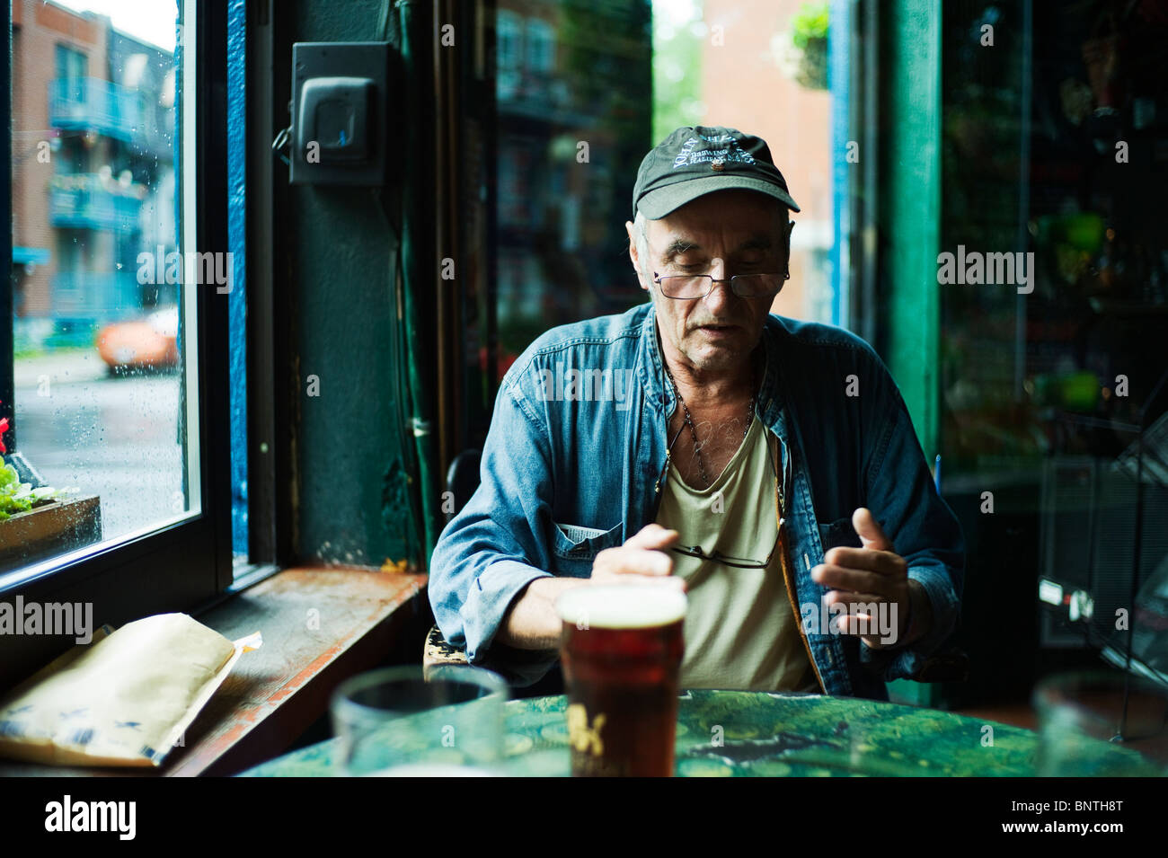 Old man gestures while sitting at bar table Stock Photo - Alamy