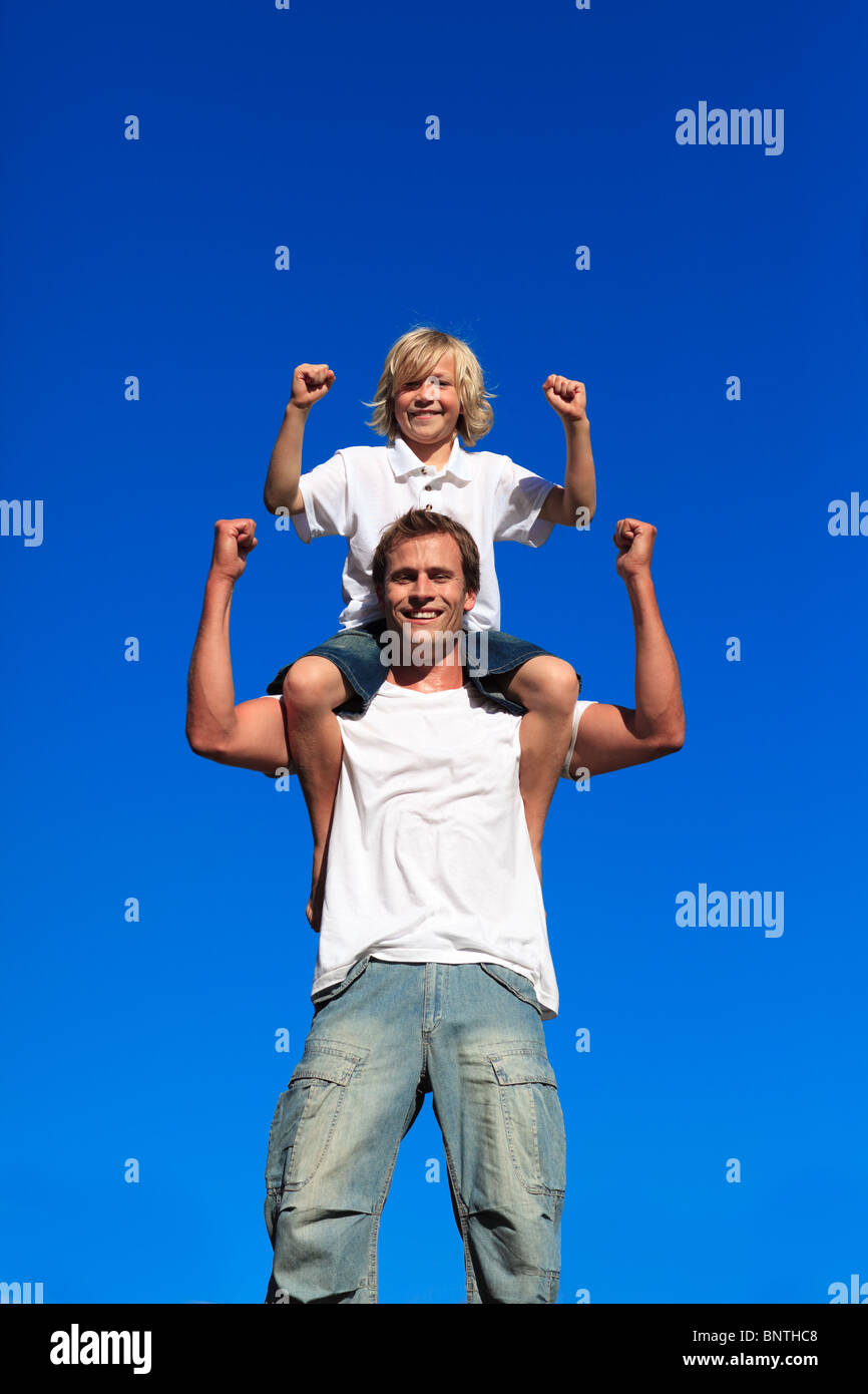 Strong son sitting on his father's shoulders Stock Photo - Alamy